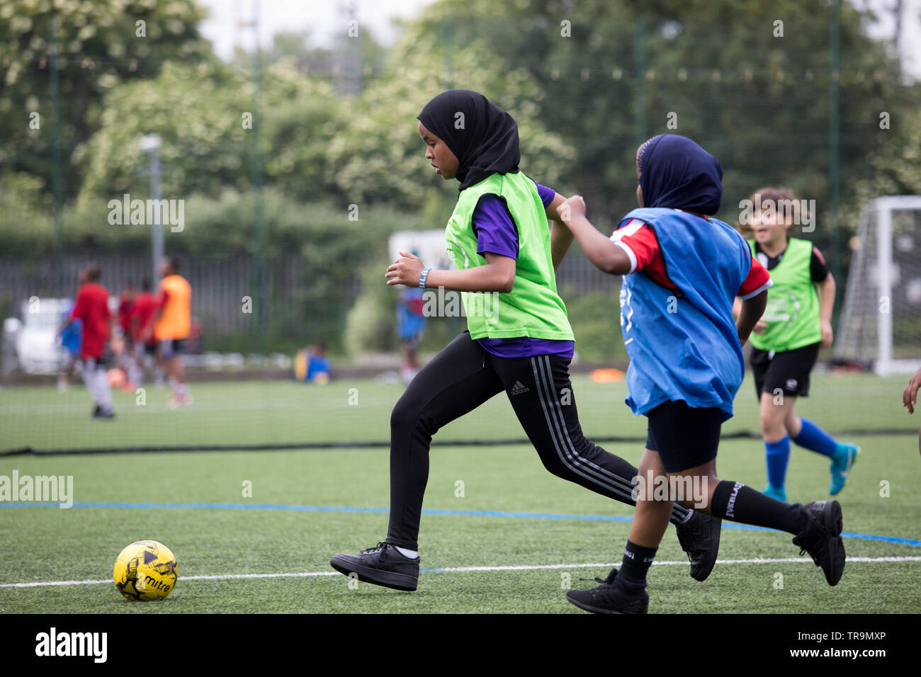 Muslim girls playing football on an astroturf training pitch. Some are ...
