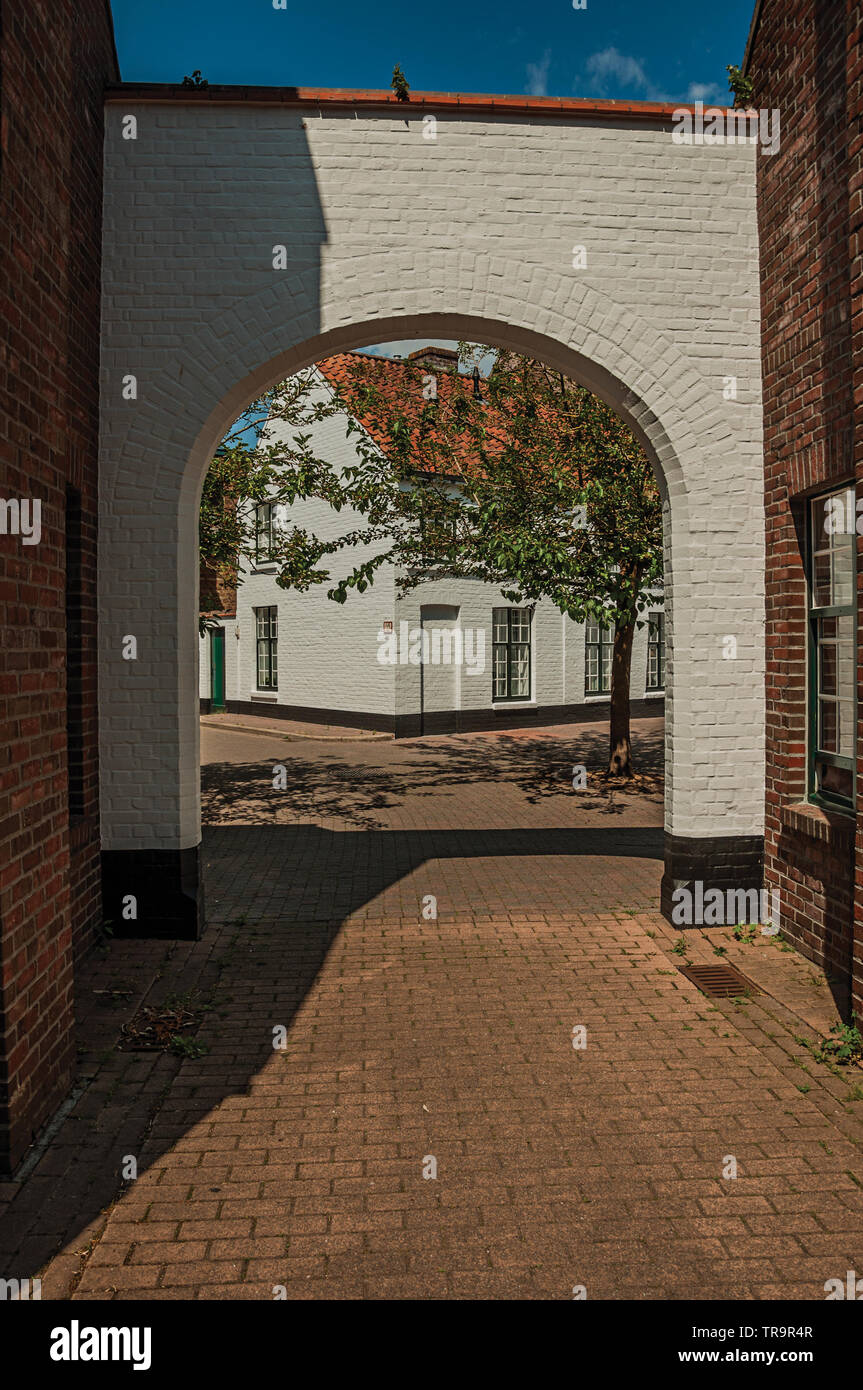 Brick portal to enter a graceful square with tree and old brick house ...