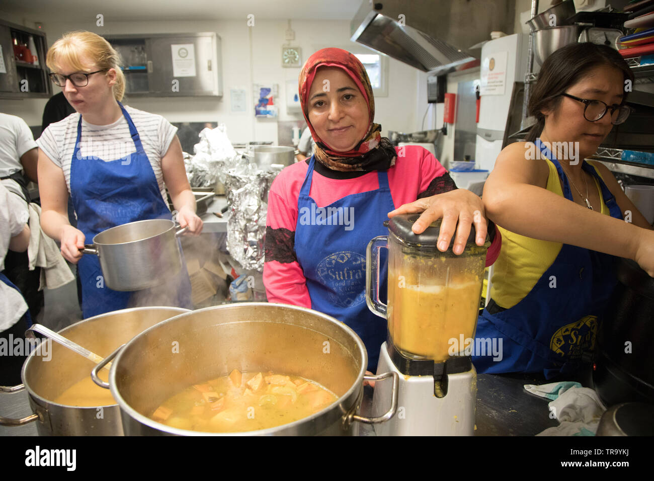 Volunteers at a community kitchen prepare a meal for diners in need ...