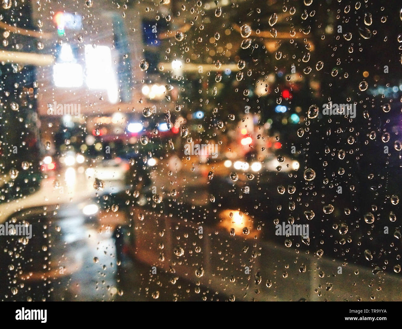 Rain drops on transparent glass window, view to a shopping mall outside ...