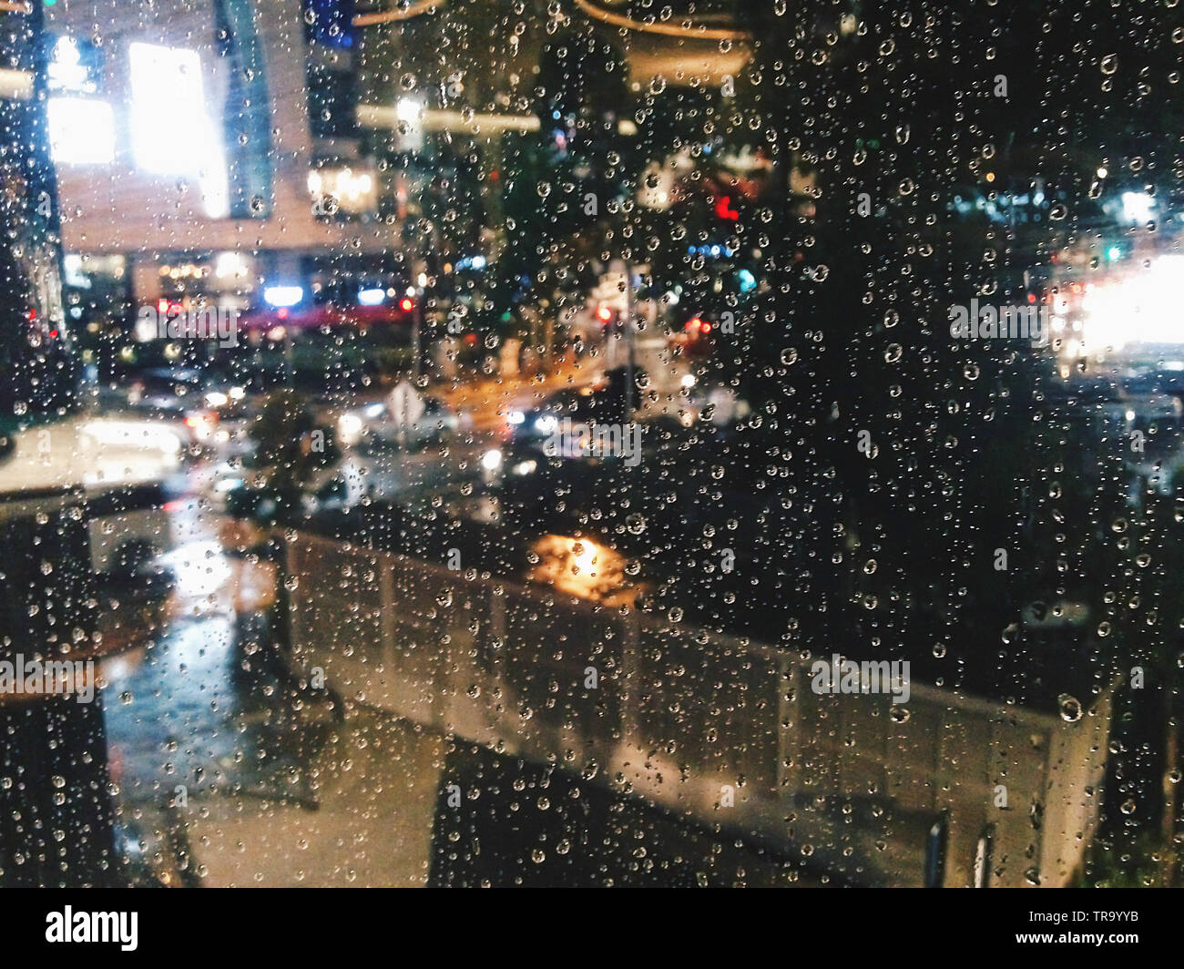 Rain drops on transparent glass window, view to a shopping mall outside ...