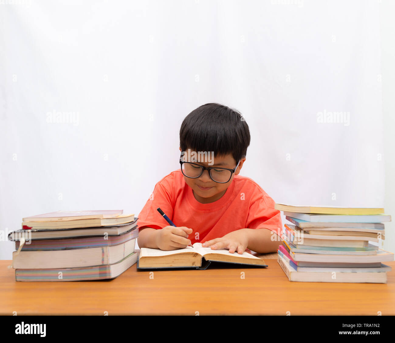 Cute a little boy writing a book on the table with on white background ...