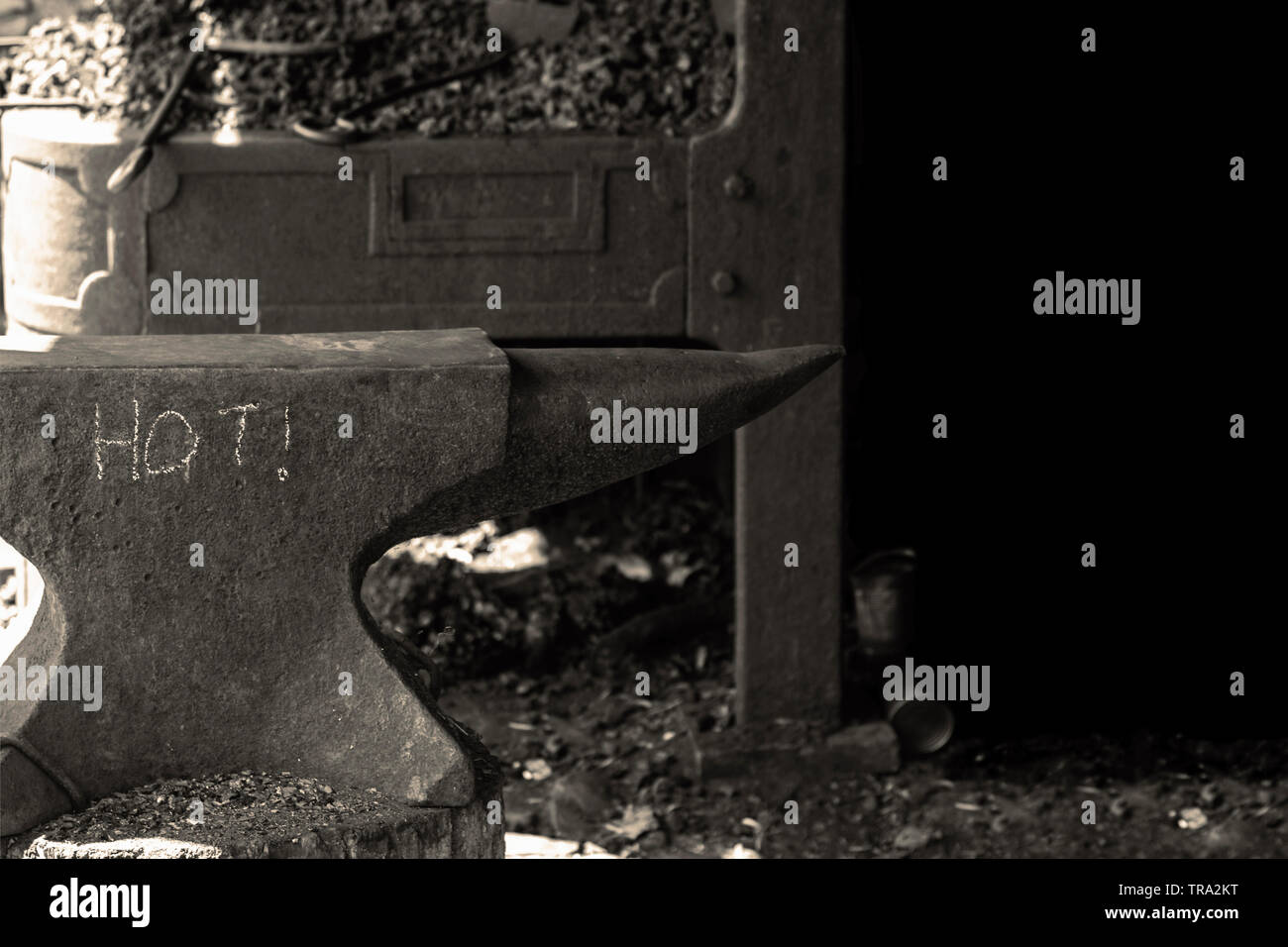 Anvil on a log with hot written on in chalk at a blacksmith. Coal ...