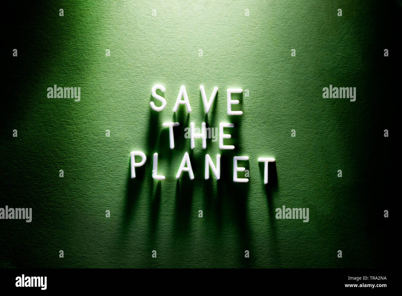 Text "Save the planet" lighted from above, flat lay, black background ...