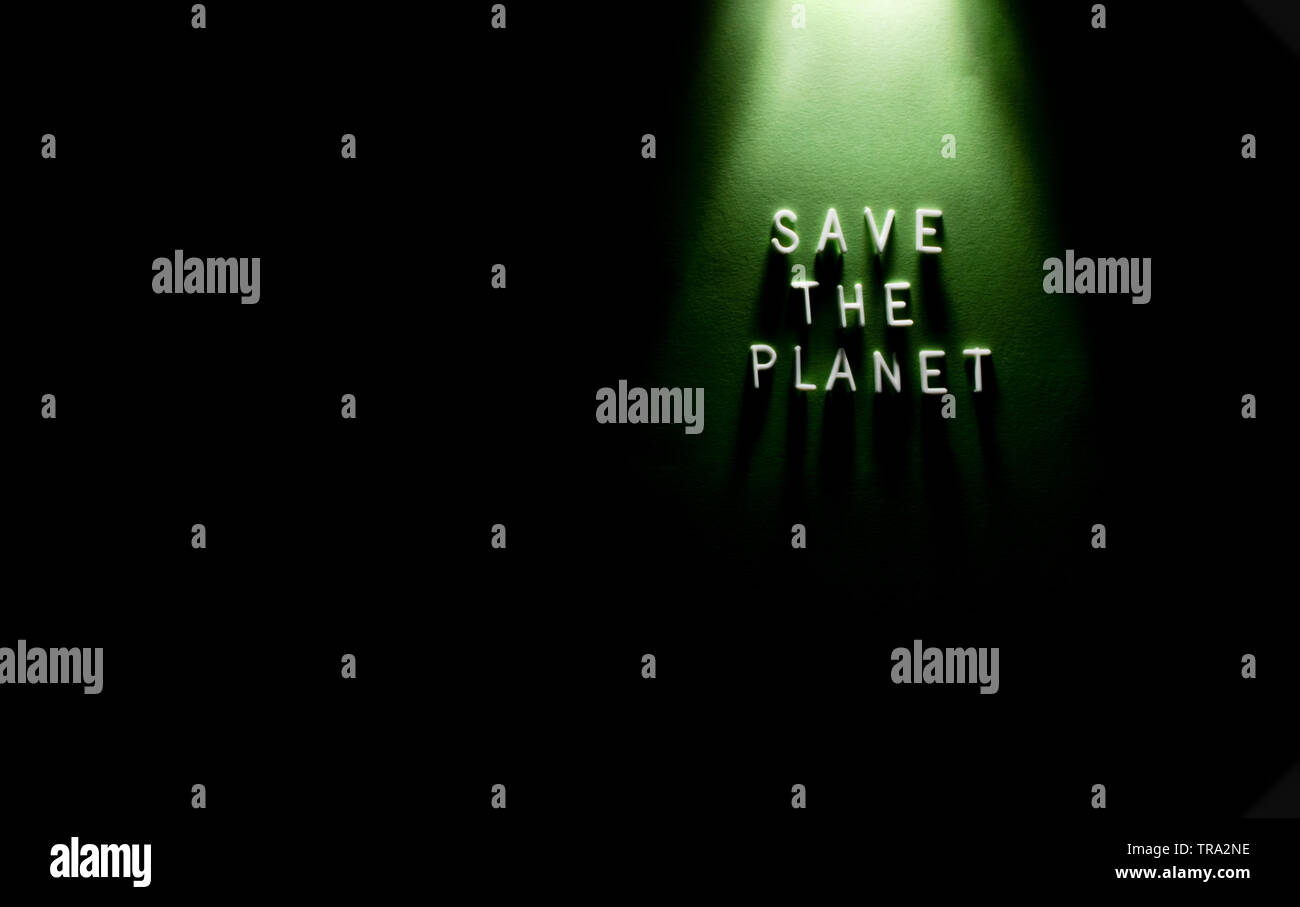 Text "Save the planet" lighted from above, flat lay, black background ...