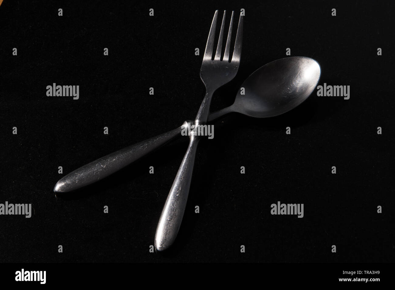 Silver Spoon and Fork on black background crossed Stock Photo - Alamy