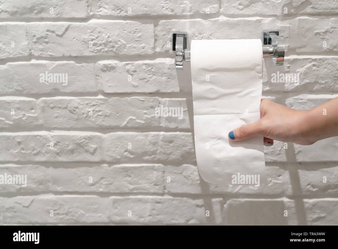 female hand pulling a white tissue paper from tissue roll in the ...