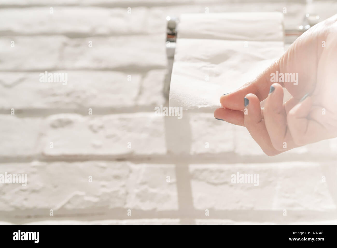 female hand pulling a white tissue paper from tissue roll in the ...