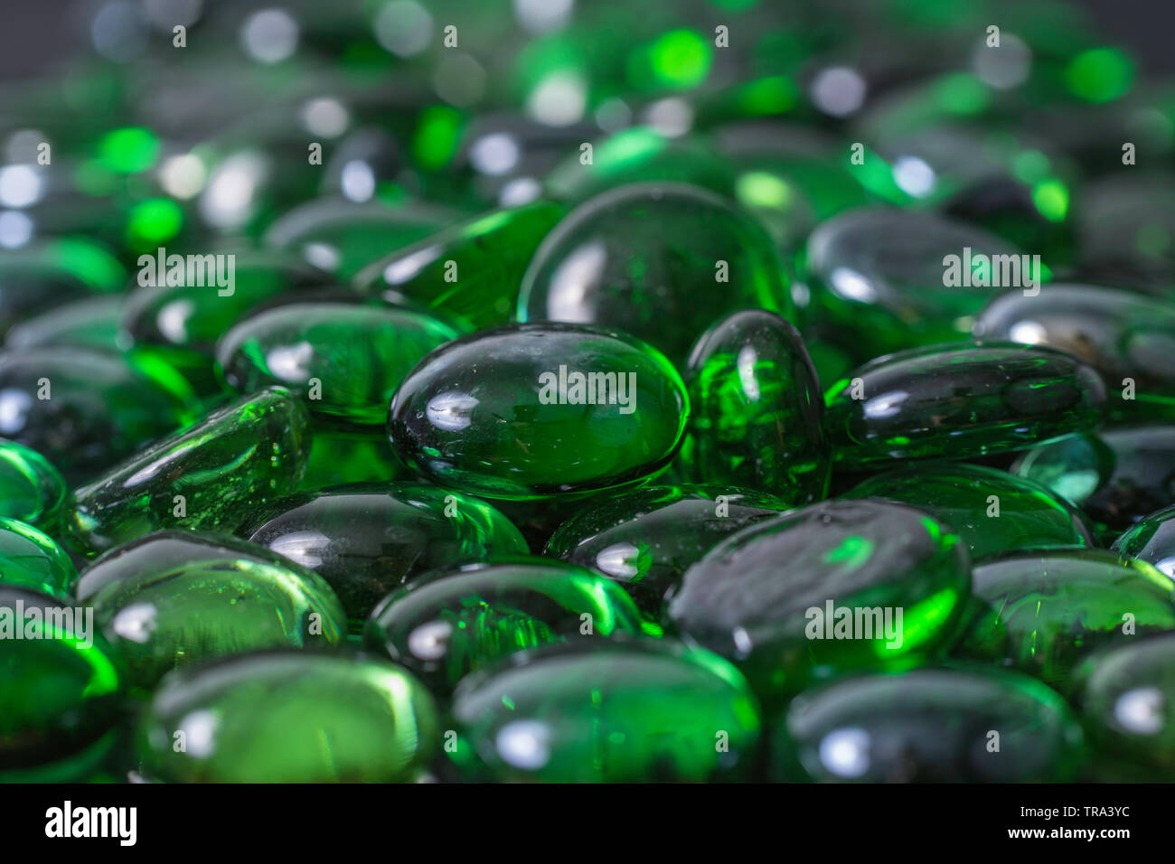 Green glass stone pebbles with other pebbles and blurred background ...