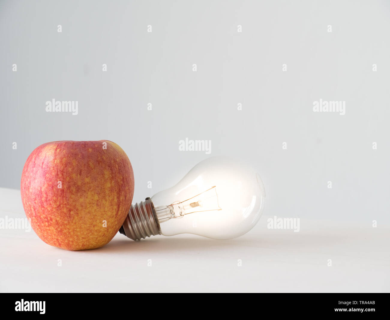 Light bulb in red apple on white background Stock Photo - Alamy