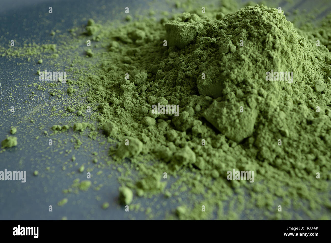 Close up pile of matcha powder on black plate. Natural matcha green tea ...