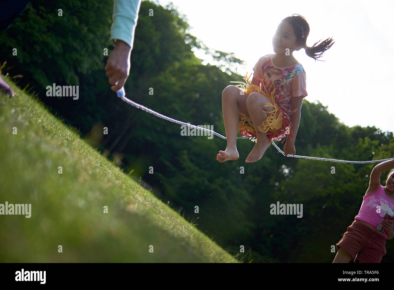 A young mother and her two young daughters playing with a skipping rope ...
