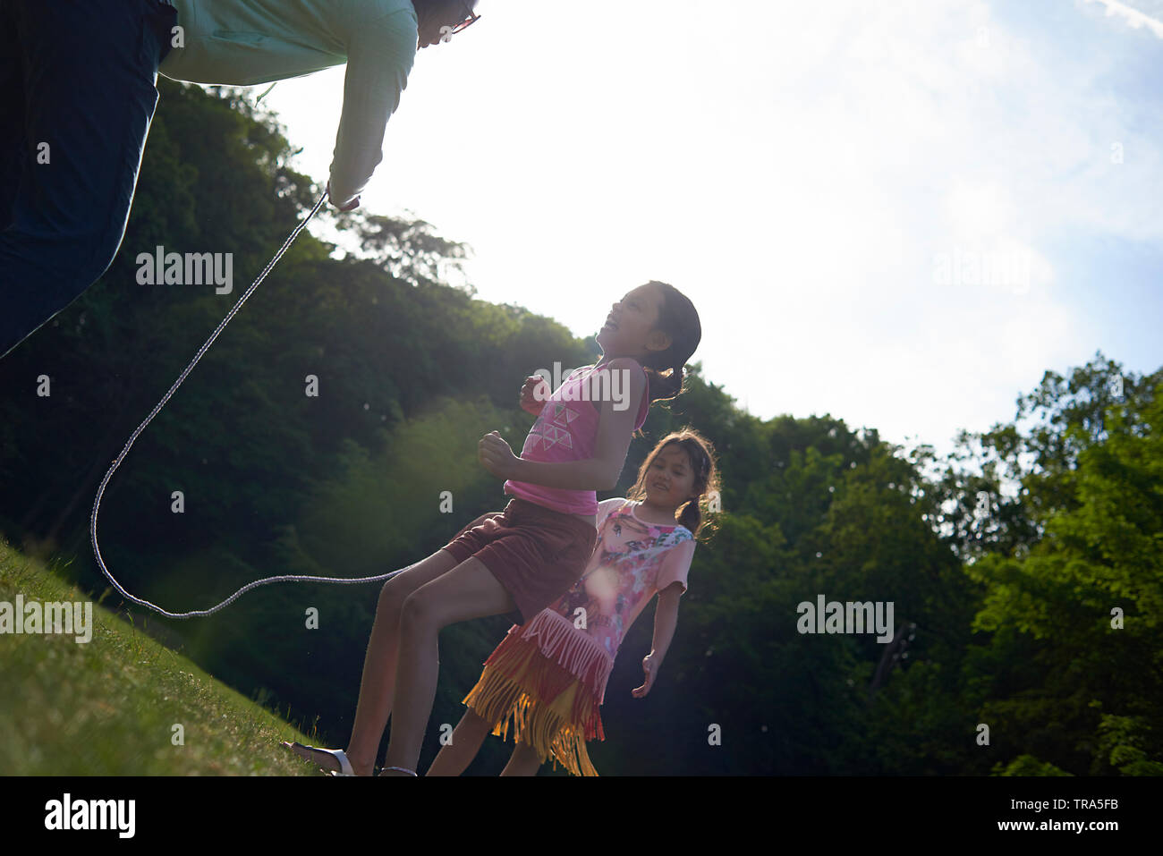A young mother and her two young daughters playing with a skipping rope ...