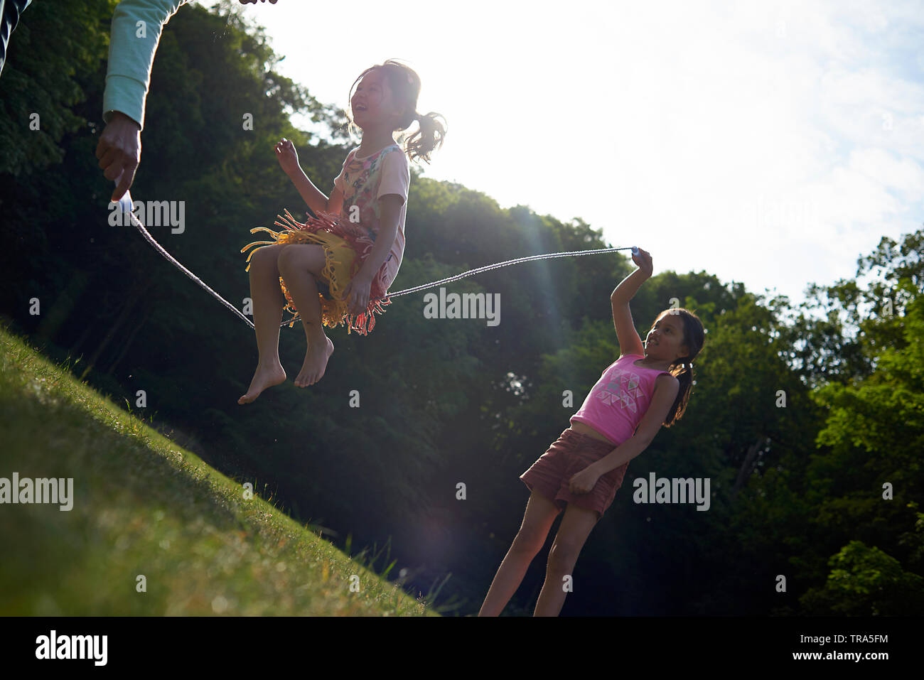 A young mother and her two young daughters playing with a skipping rope ...