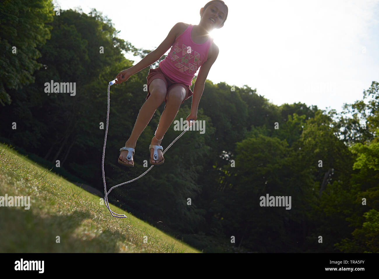 A young mother and her two young daughters playing with a skipping rope ...