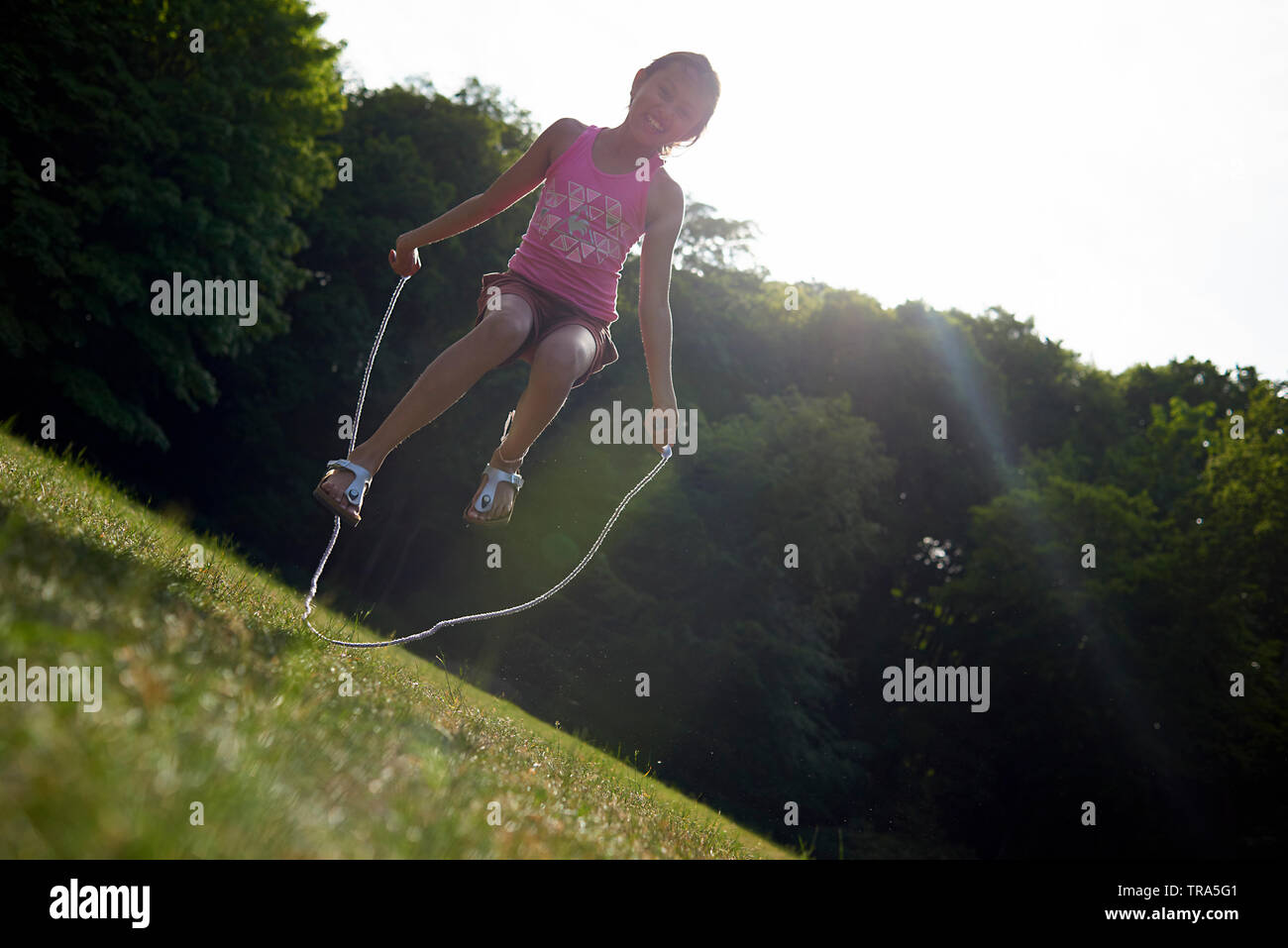 A young mother and her two young daughters playing with a skipping rope ...