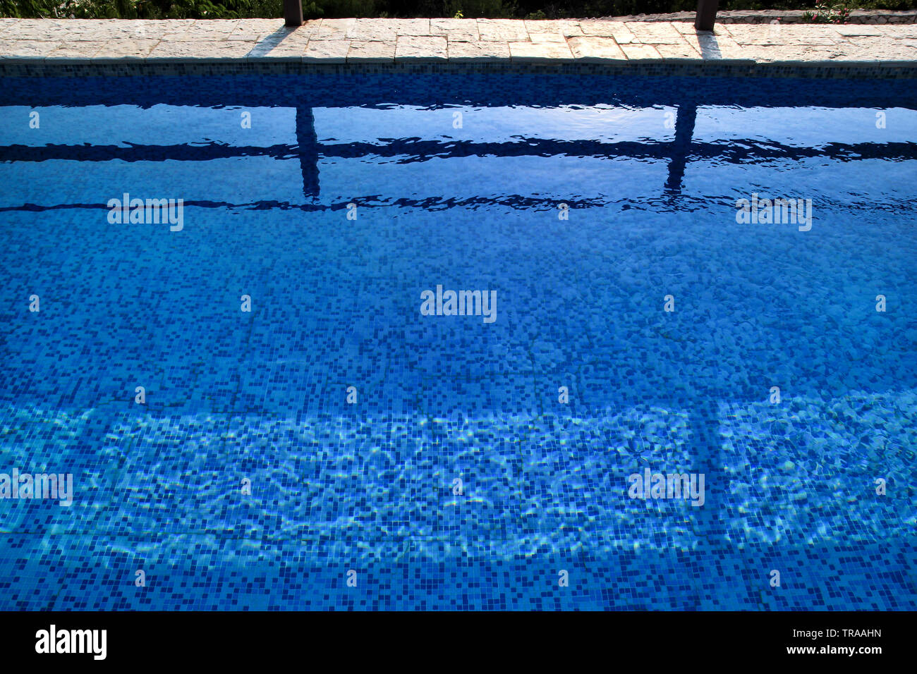Blue ripped water in swimming pool in tropical resort with edge of ...