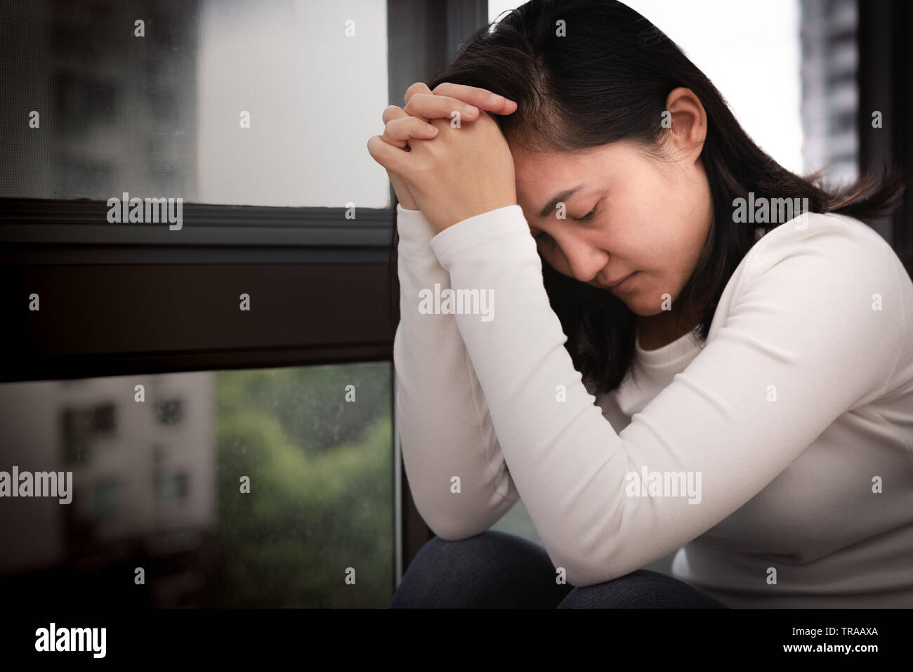depressed women sitting near window and praying, alone, sadness ...