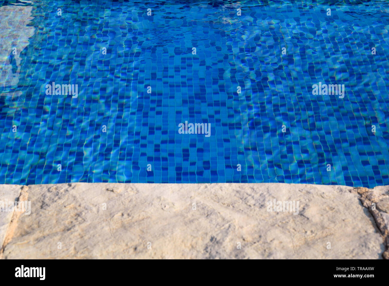 Blue ripped water in swimming pool in tropical resort with edge of ...