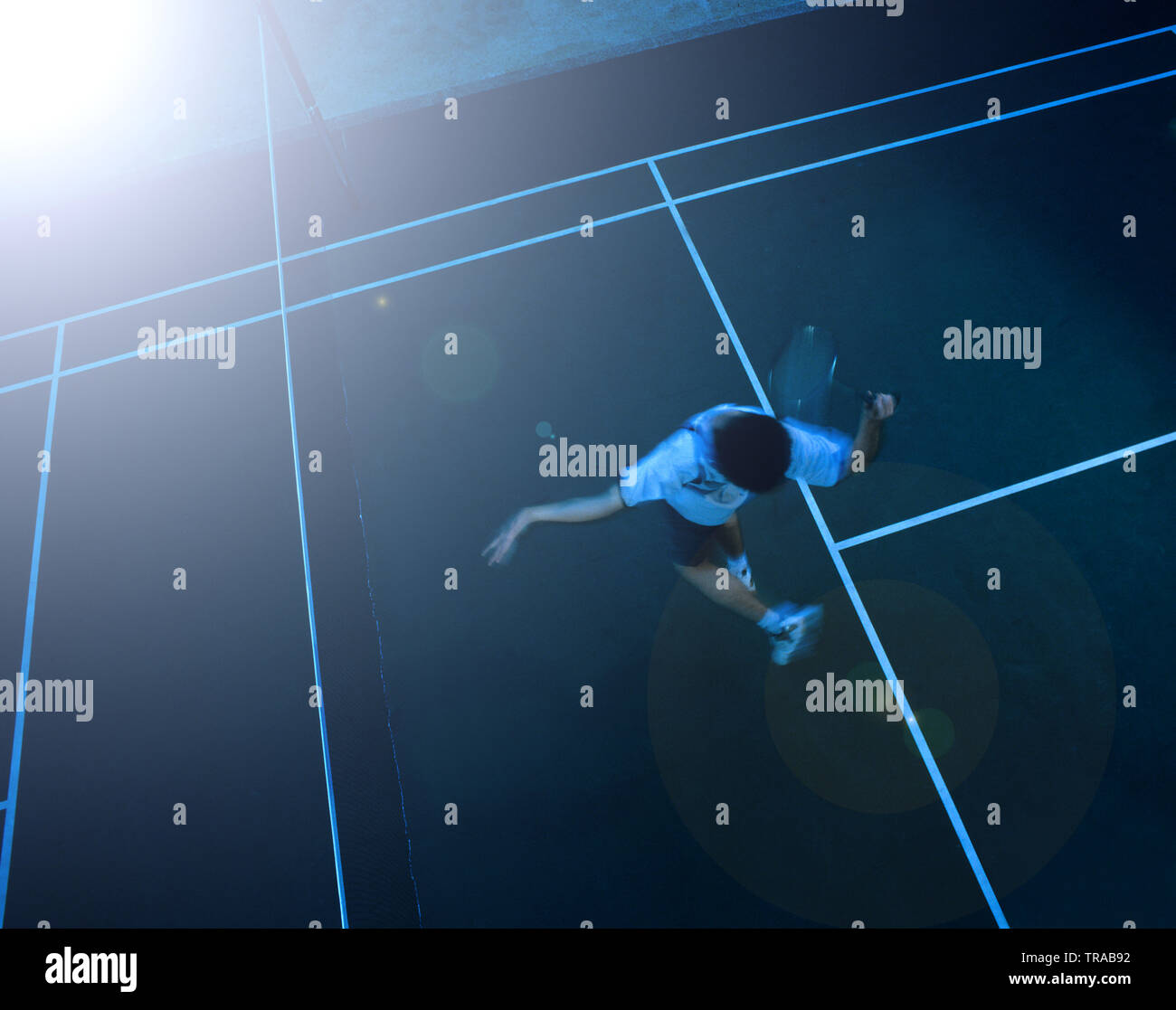Healthy fit man jumping high on a badminton court smashing the shuttle ...