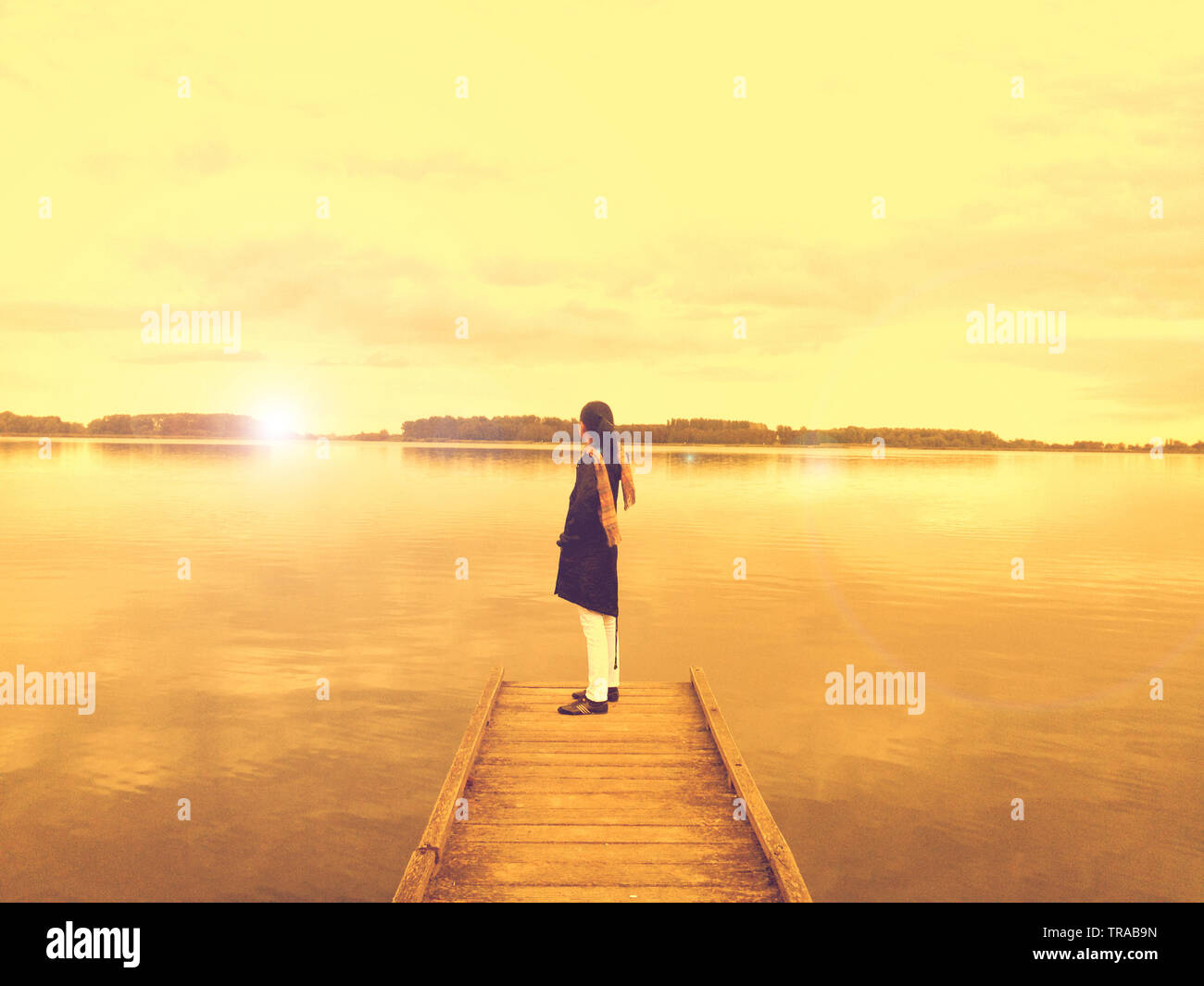 Amazing landscape at a quiet lake of a woman standing at the end of a ...