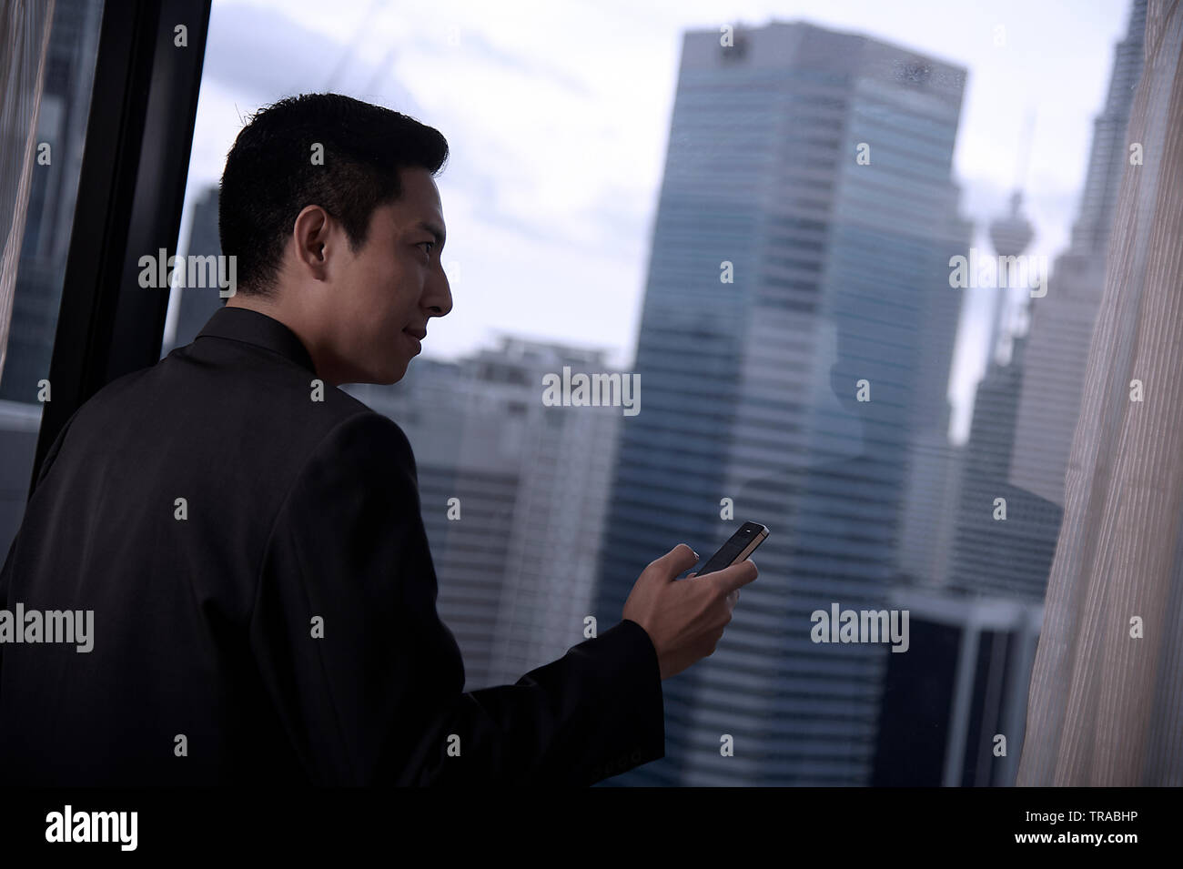 Portrait of an affluent modern Asian business man standing at a window ...