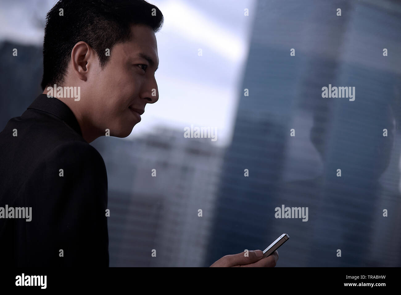 Portrait of an affluent modern Asian business man standing at a window ...