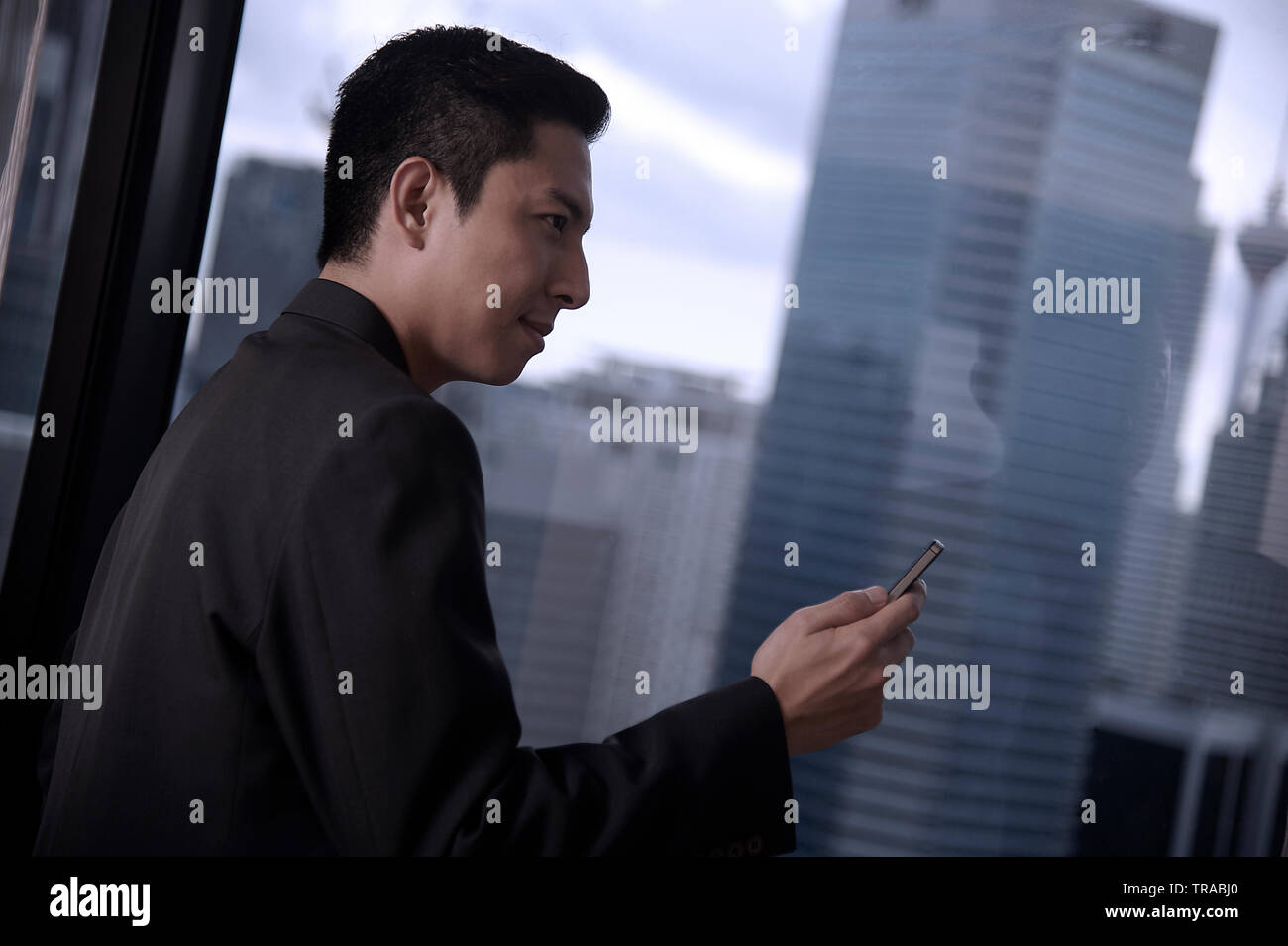 Portrait of an affluent modern Asian business man standing at a window ...