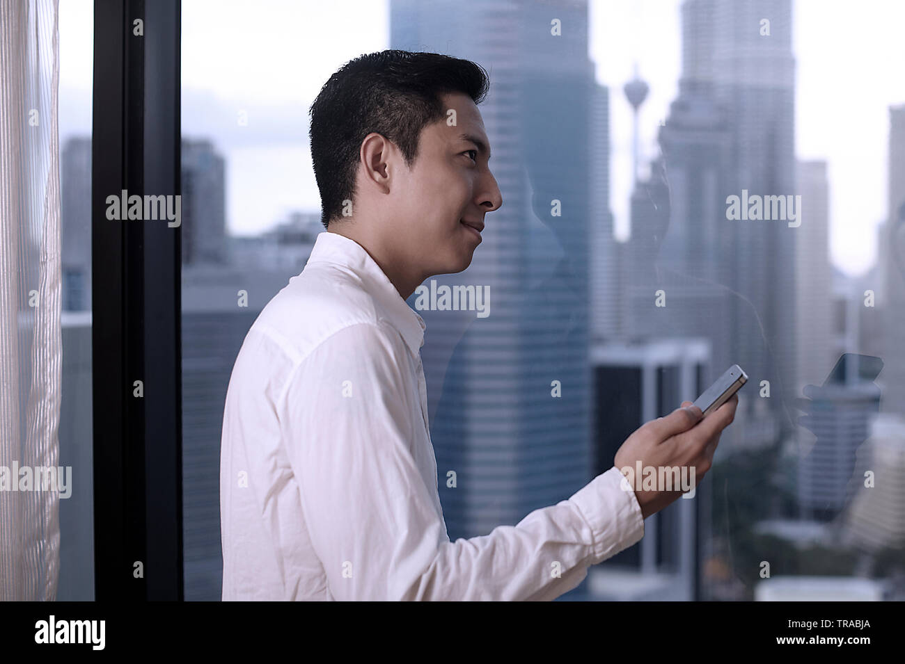 Portrait of an affluent modern Asian business man standing at a window ...