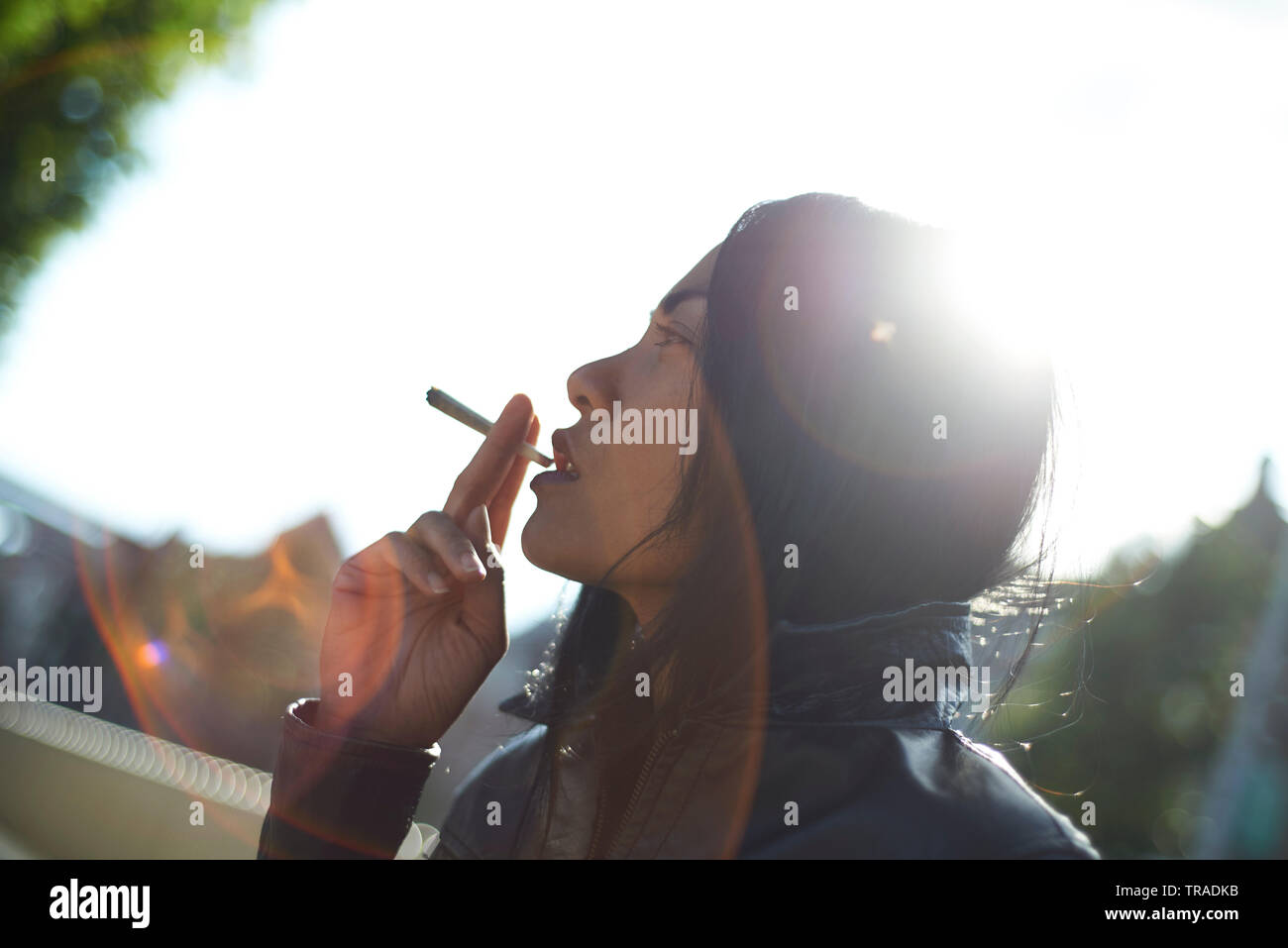 Asian tourist enjoying smoking a spliff with marijuana in summer ...