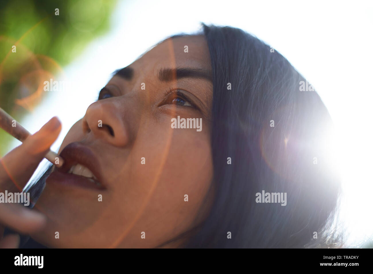 Asian tourist enjoying smoking a spliff with marijuana in summer ...