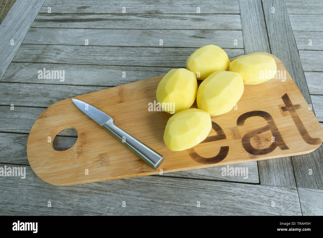 peeled potatoes and sliced French fries on a wooden board and a sharp ...