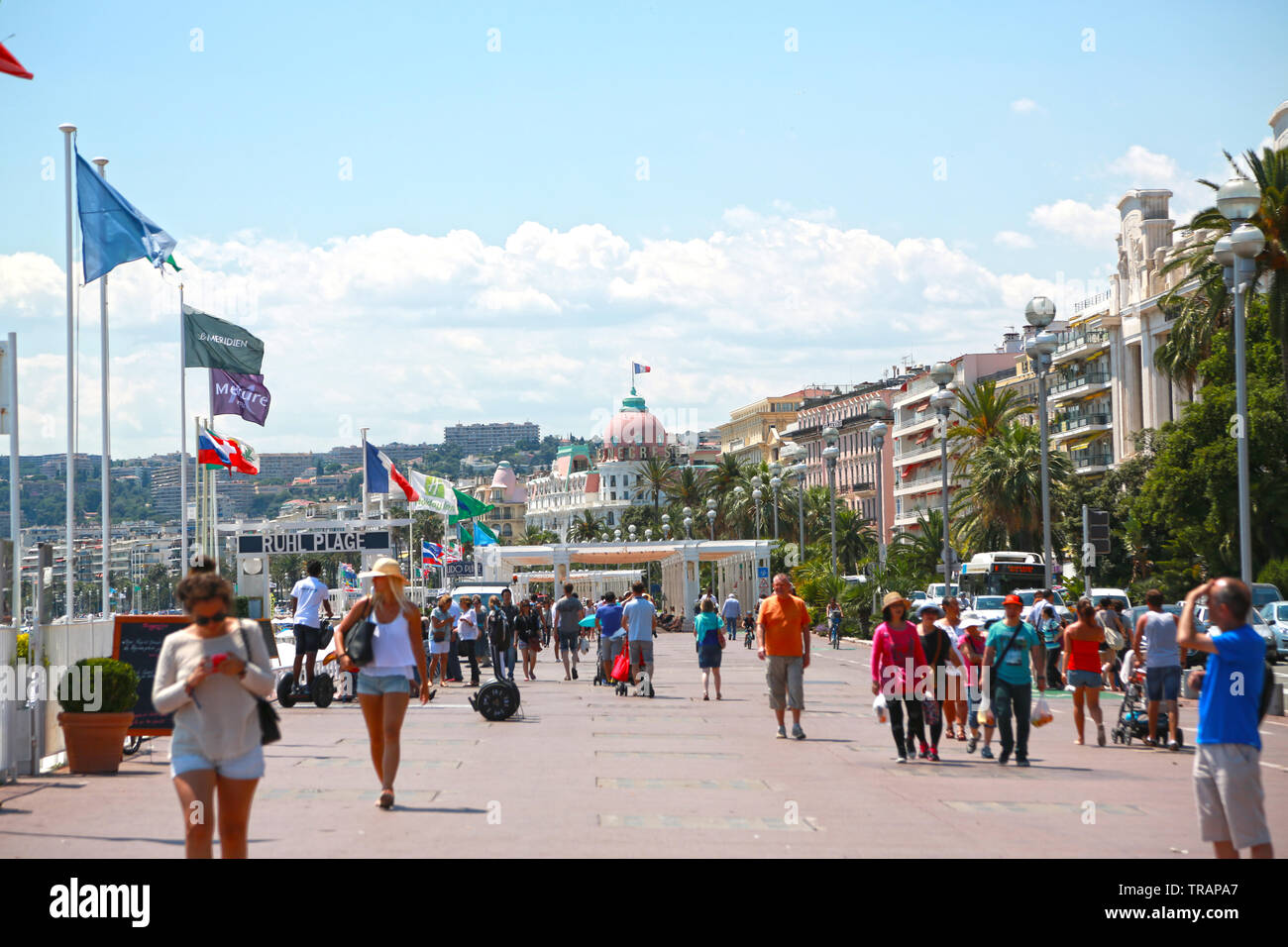 People walk along the promenade at Nice, enjoying a beautiful summer ...