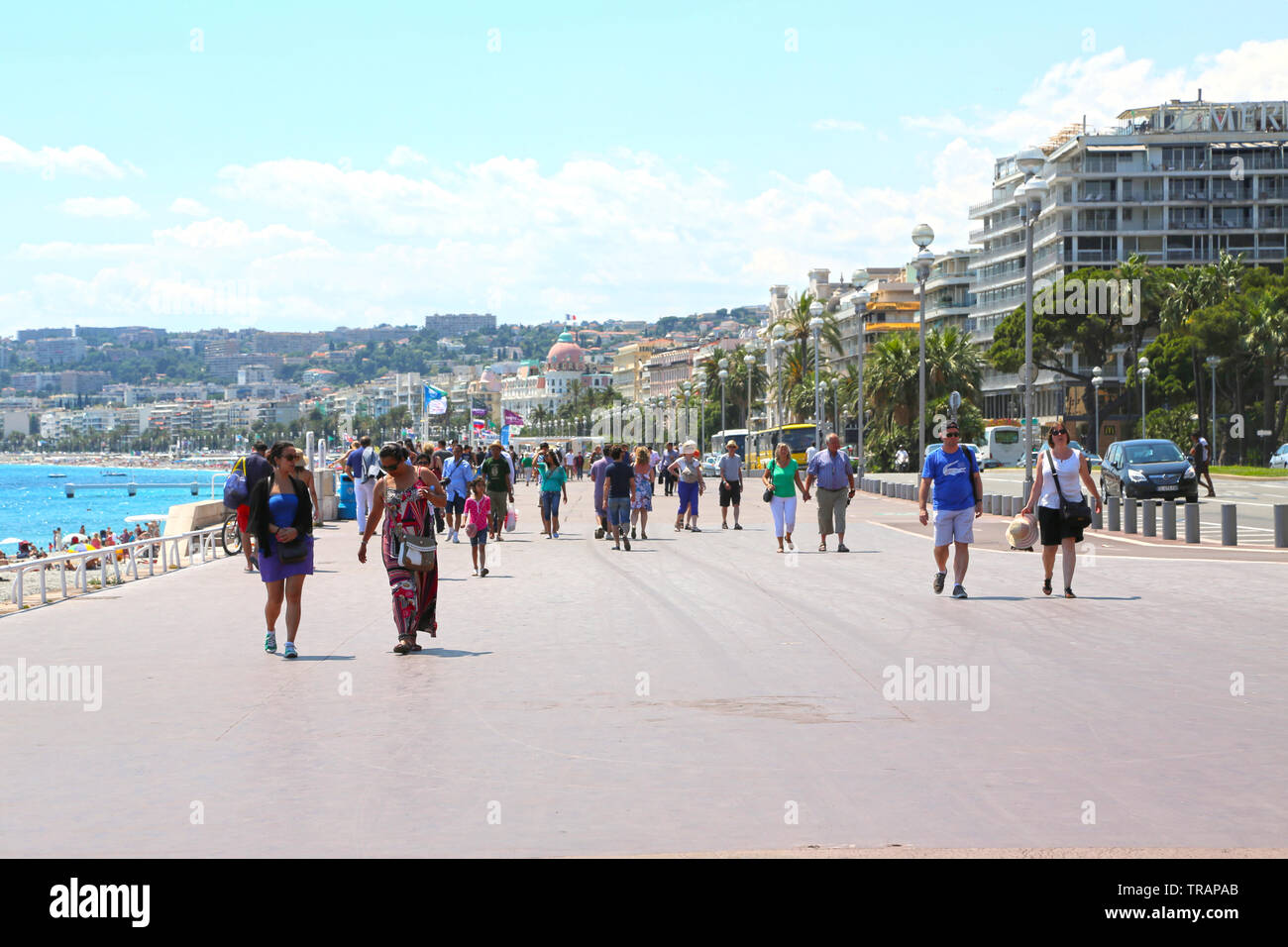 People walk along the promenade at Nice, enjoying a beautiful summer ...