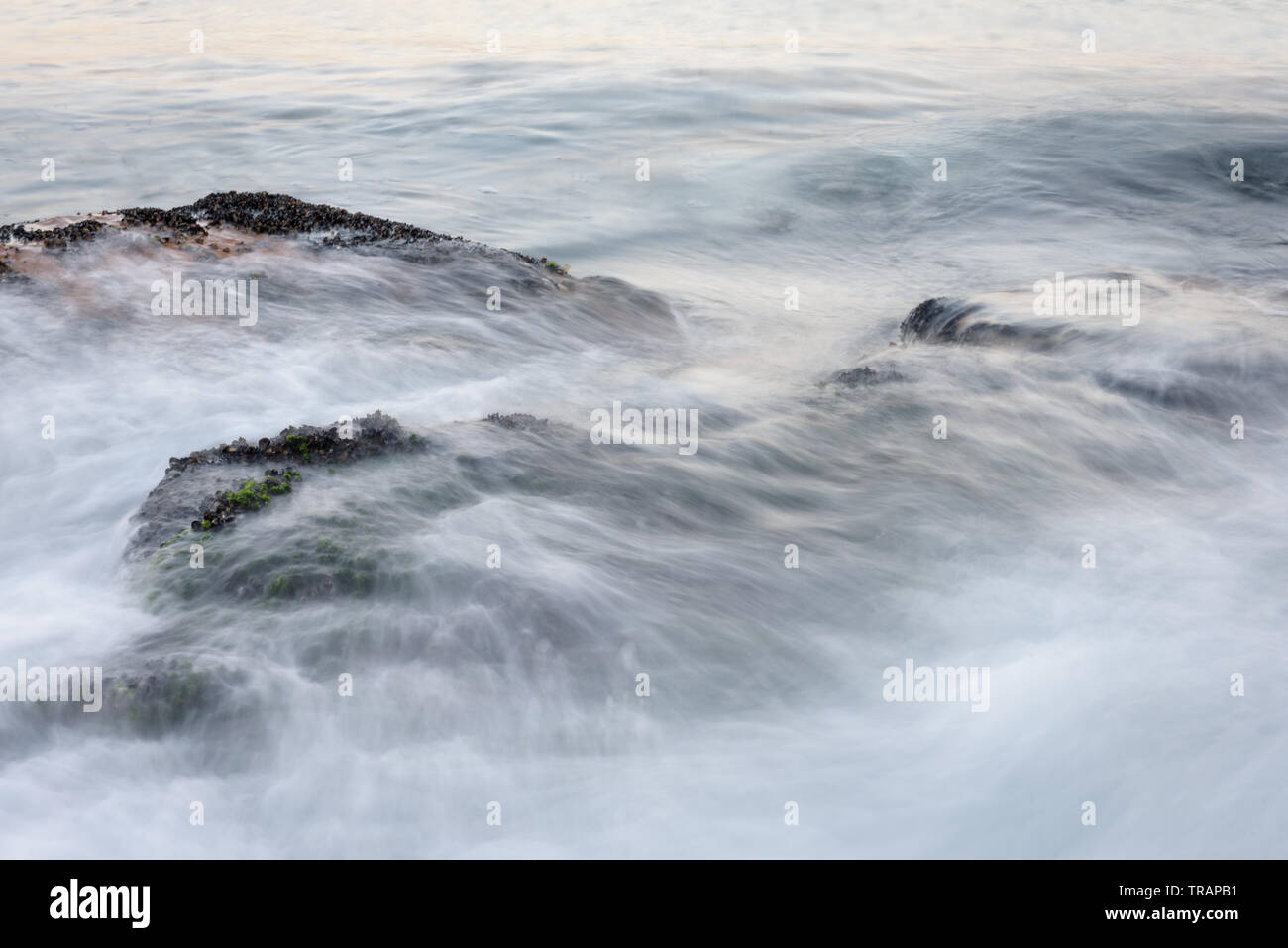 Heavy seas wash across mussel covered rocks on the False Bay coastline ...