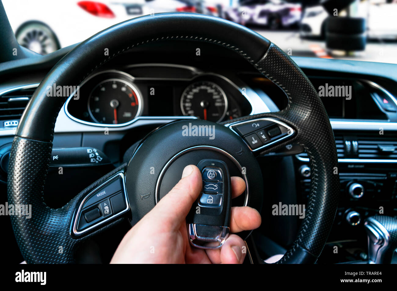 Man's hand holding a wireless car key in black leather interior. Modern ...