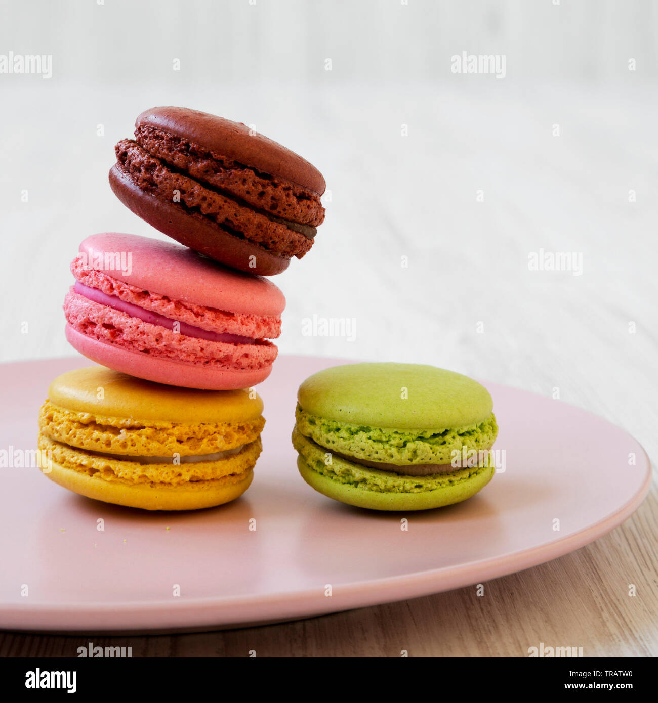 Colorful macarons on a pink plate over white wooden background, side ...