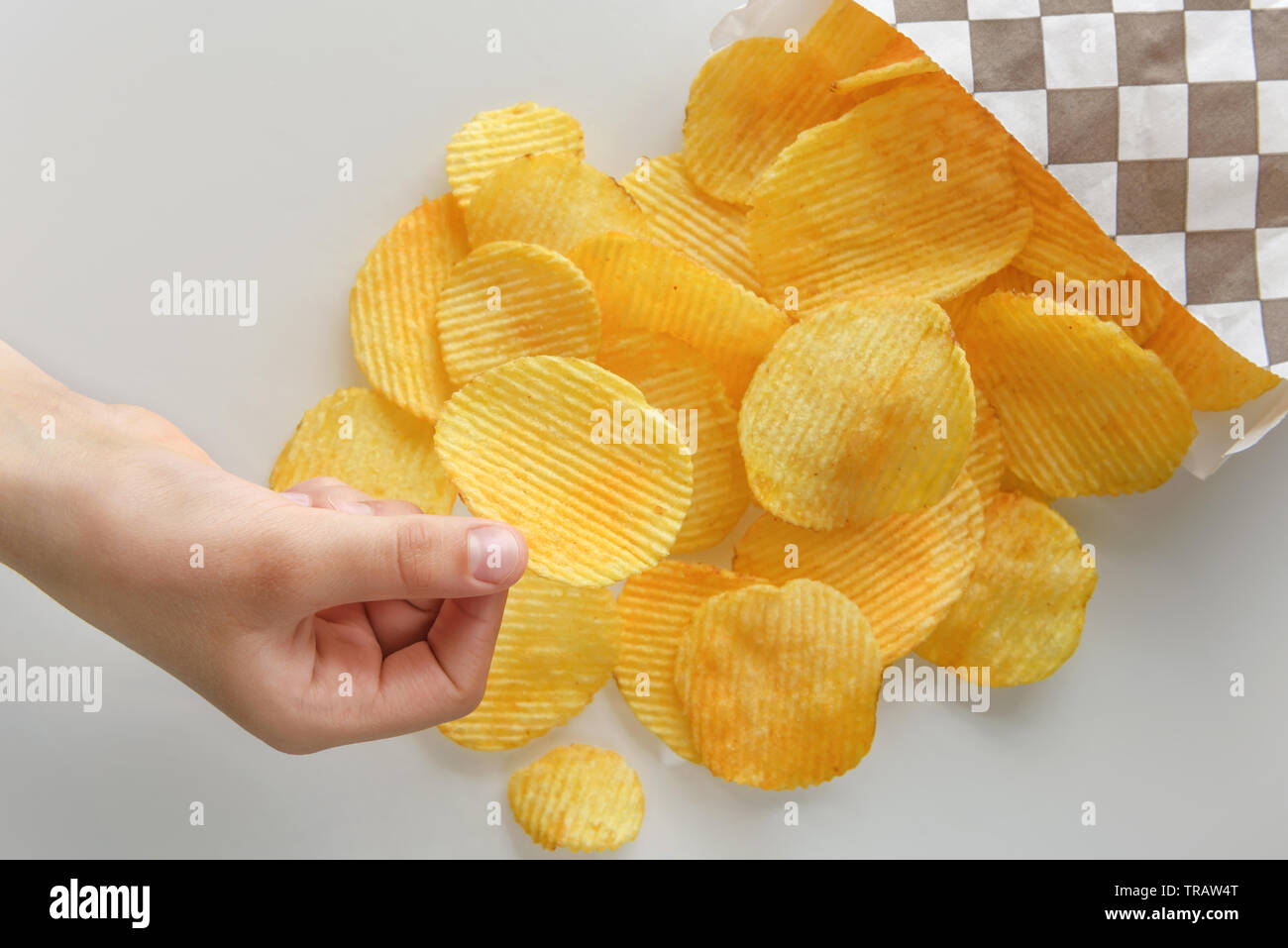 The human hand is holding a potato chip. Golden wavy potato chips are ...