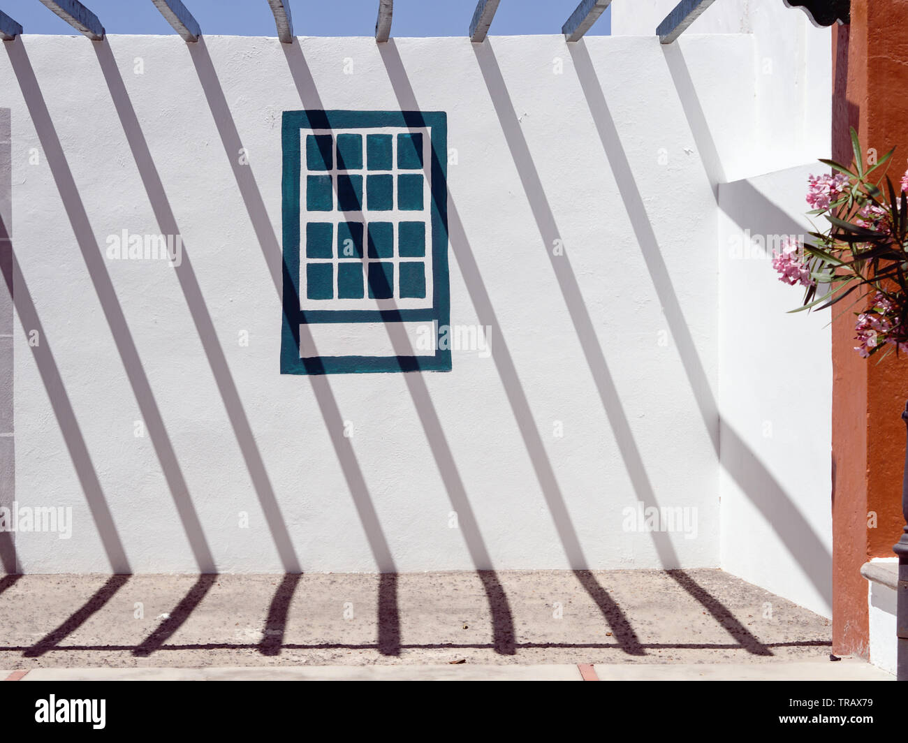 strong shadows of a metal grid cast a graphic pattern on a white wall ...