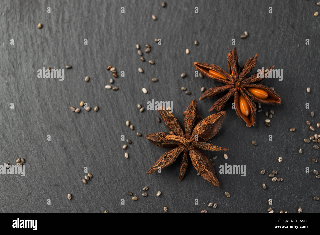 Dry anise flowers top view on black stone board and dry chia seeds ...
