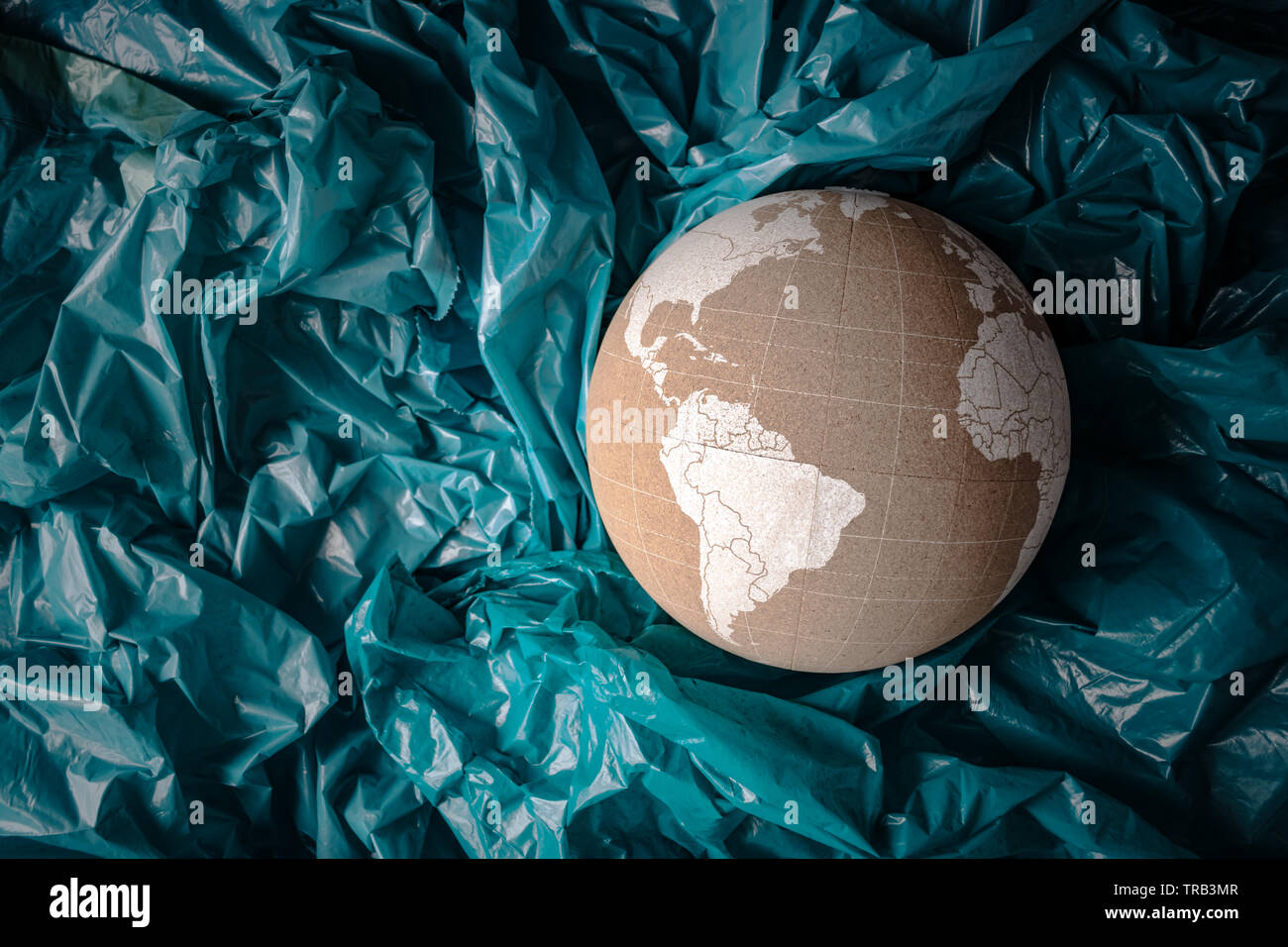 Cork globe sinking in blue plastic ocean. Creative concept of ocean ...