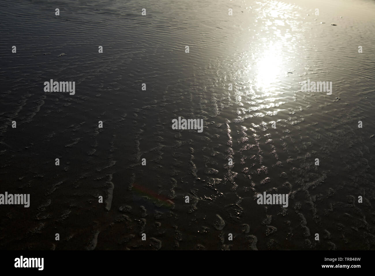 Wave patterns on the sand in shallow water with the sunshine reflecting ...