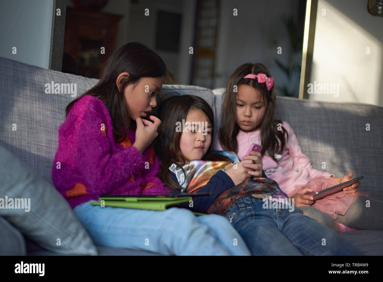 Three Young Asian Girls Sitting On The Sofa Together Gaming On Their