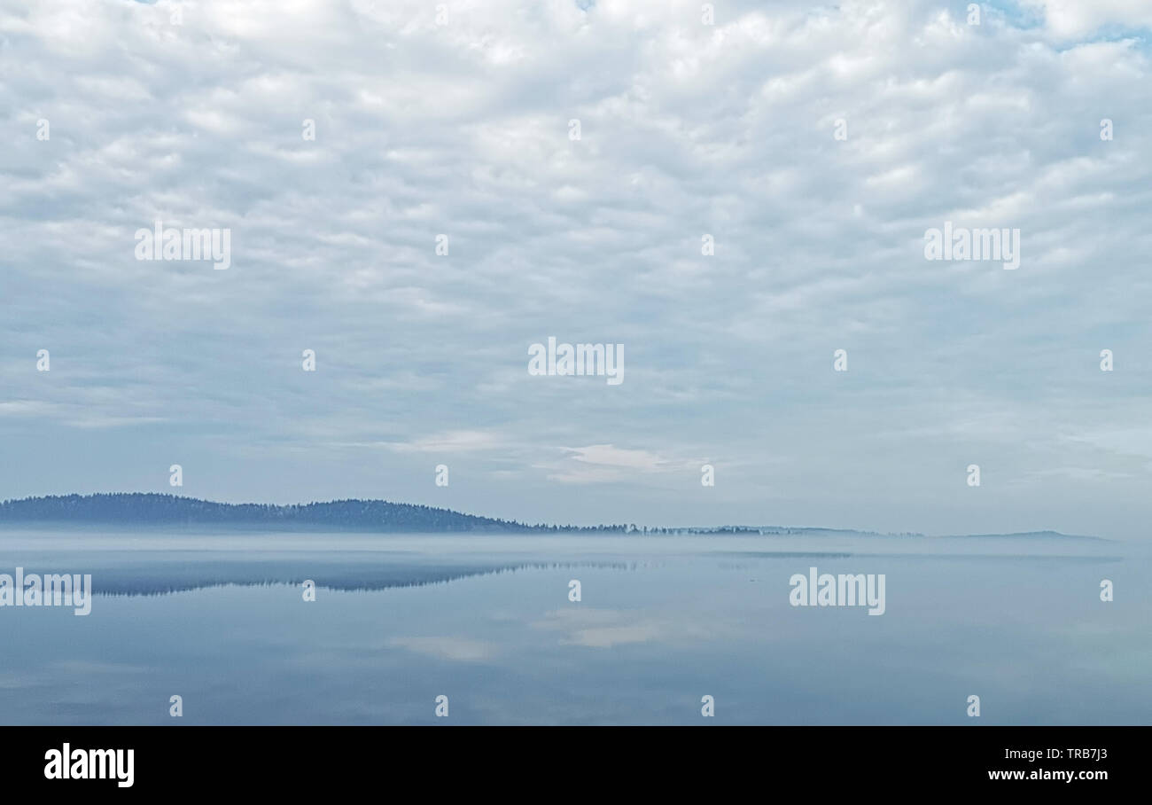 Early morning landscape with calm lake and forest under heavy ...
