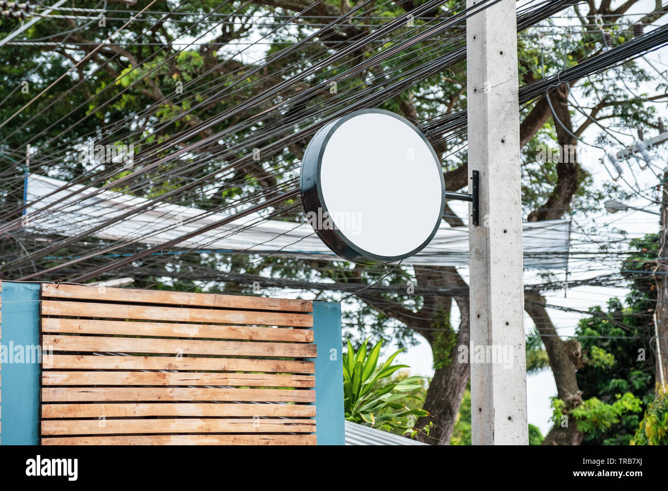 Rounded modern signboard hanging on mortar pole with wire disorderly ...