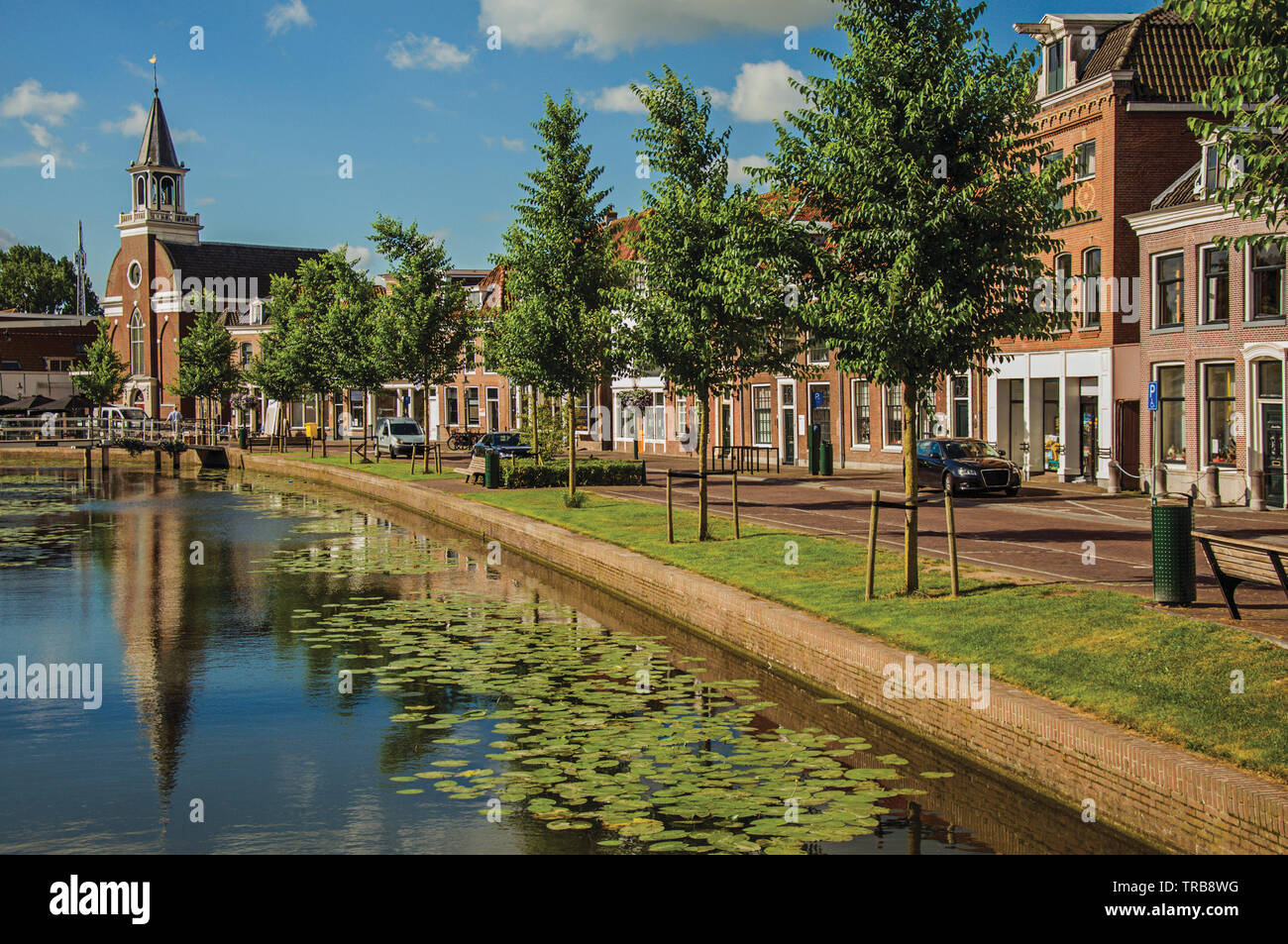 Tree-lined canal with bascule bridge, church, brick houses in street on ...