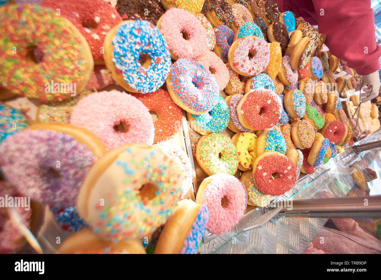 Lots of colorful donuts on display at a market stall to buy in bright ...