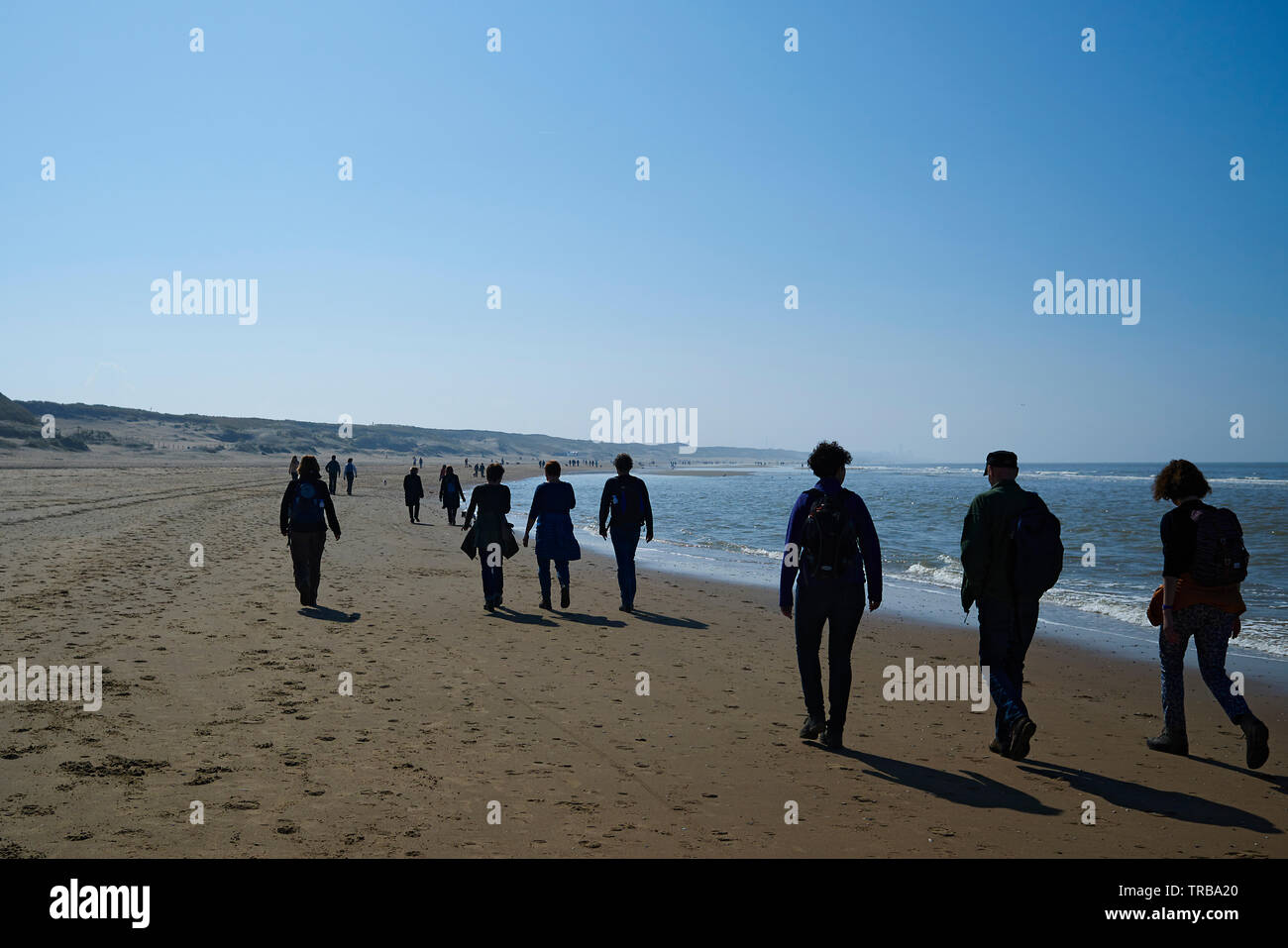 Groups of people enjoying a walk along the beach in bright srping ...