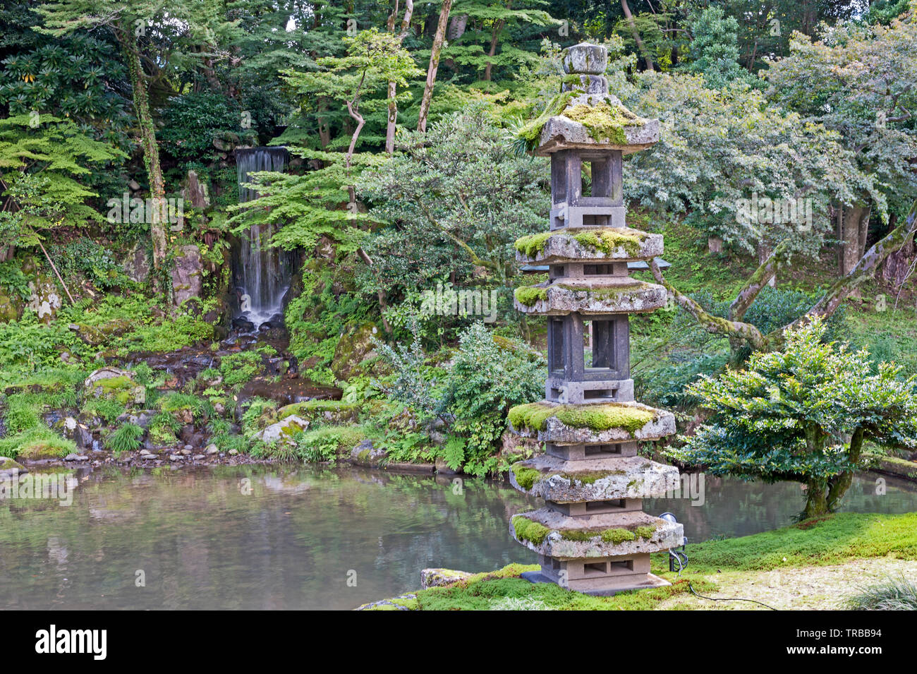 Tall Japanese lantern in foreground of Japanese garden at Kenroku-en ...