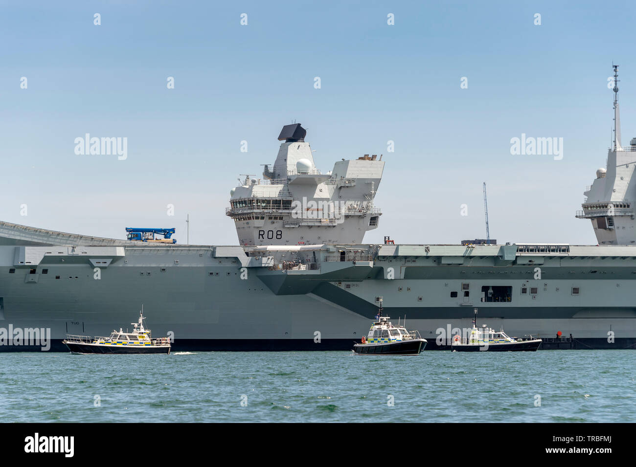 HMS Queen Elizabeth in Portsmouth Harbour with three police boats ...